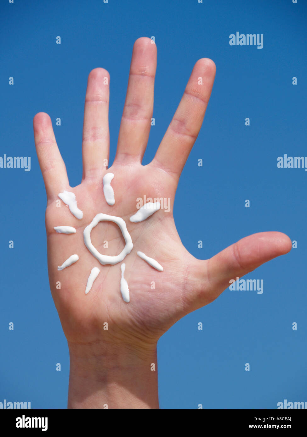 Girls hand with sun drawn with suncream against blue sky Stock Photo ...