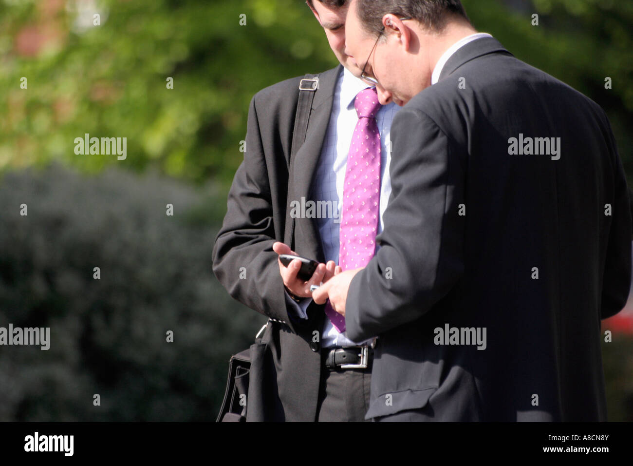 2 business men making plans or appointments with their palm tops or ...
