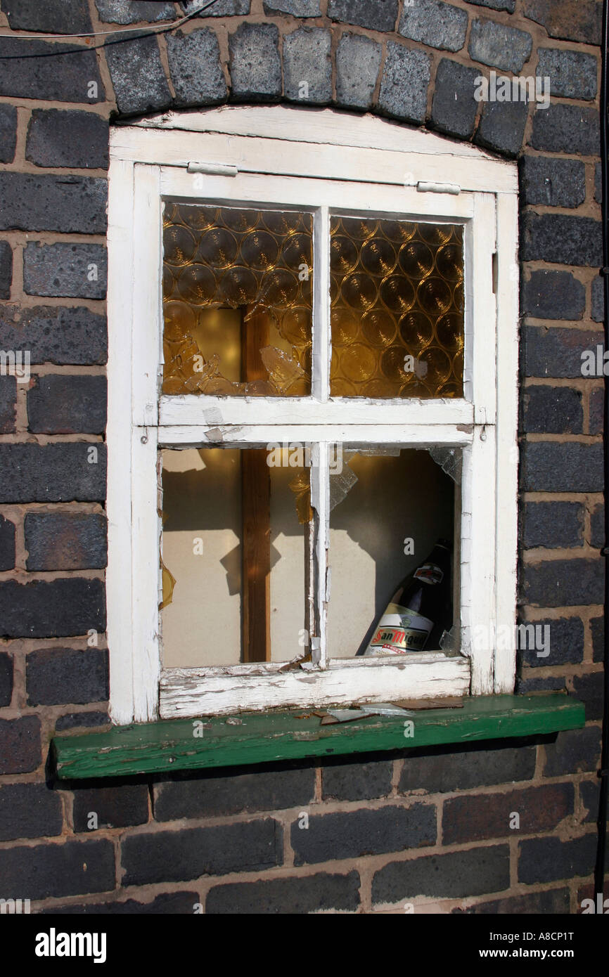 smashed window with empty bottle of beer laying inside Stock Photo - Alamy