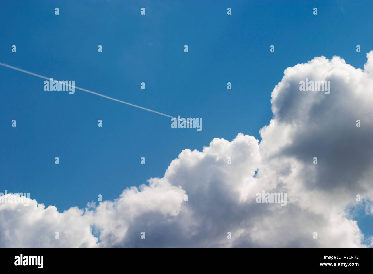 Jet airplane making vapor trail or contrail in sky with big white ...