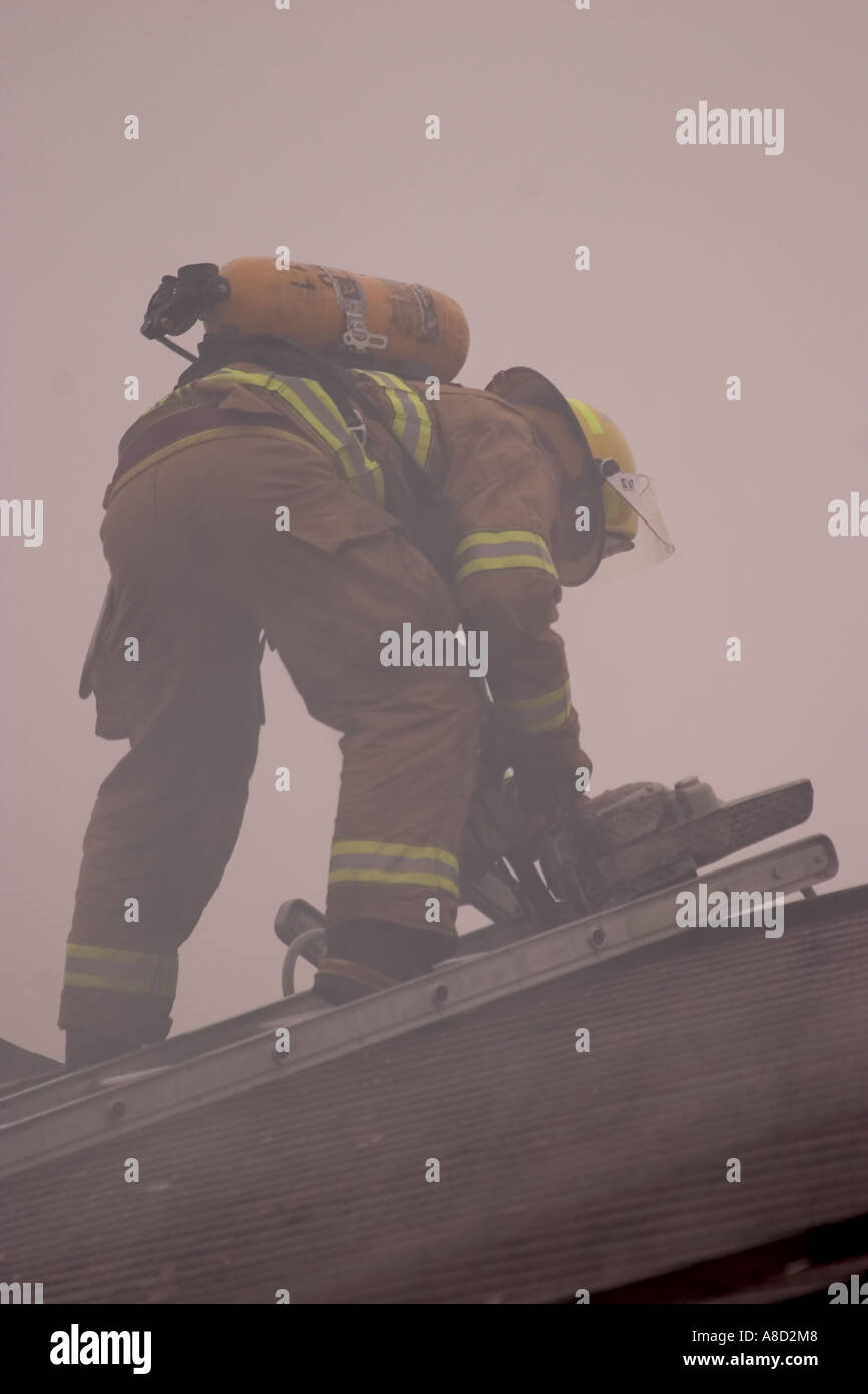 Fireman on the roof at a commercial fire getting ready to vent the roof ...
