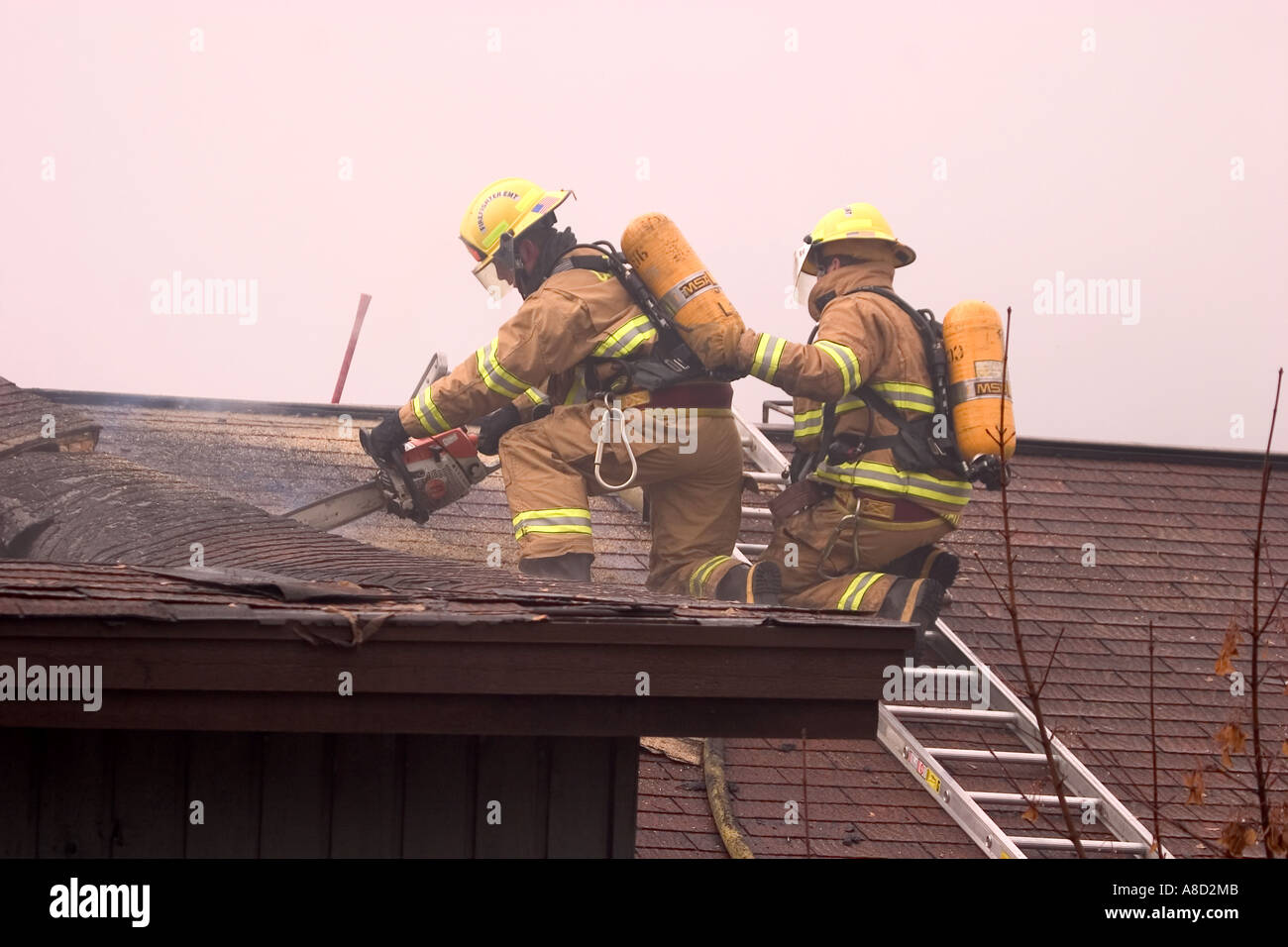 Two firemen venting a roof of a building fire with a chainsaw Stock ...