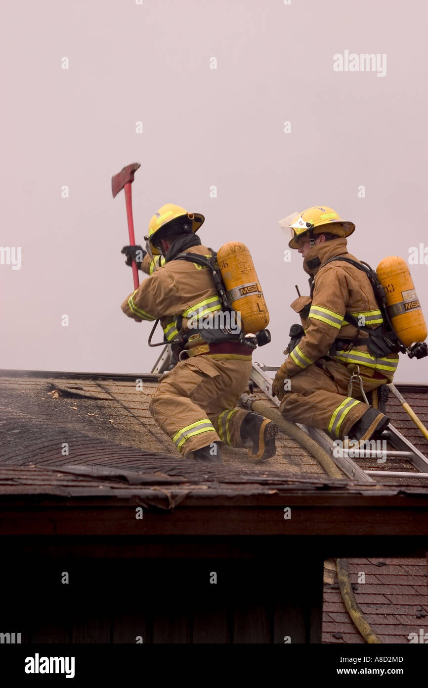 Two firemen venting a roof of a building fire with an axe Stock Photo ...