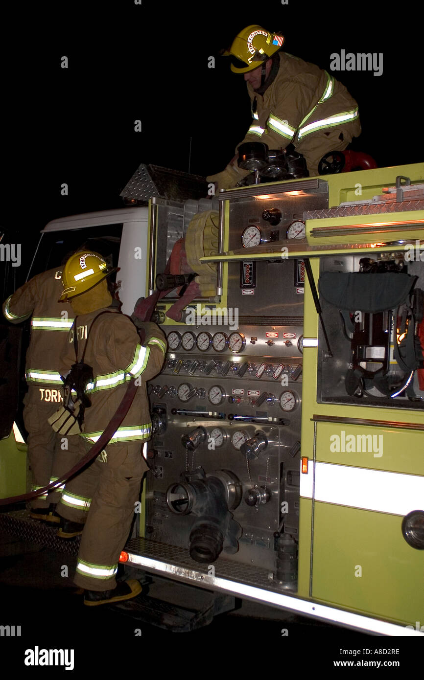Firemen loading hose back on fire truck at a night fire drill Stock ...