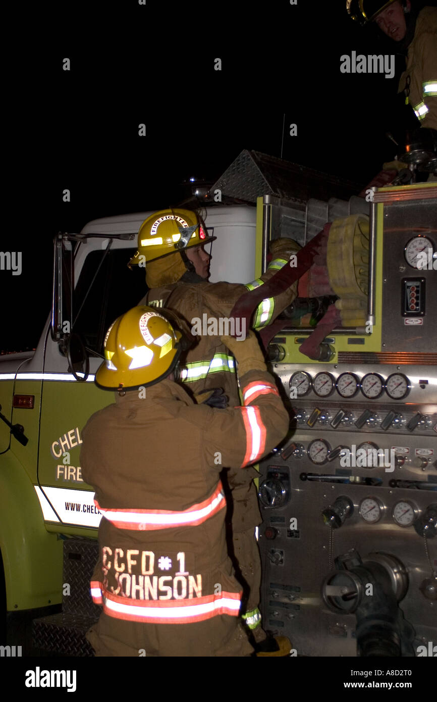 Firemen loading hose back on fire truck at a night fire drill Stock ...