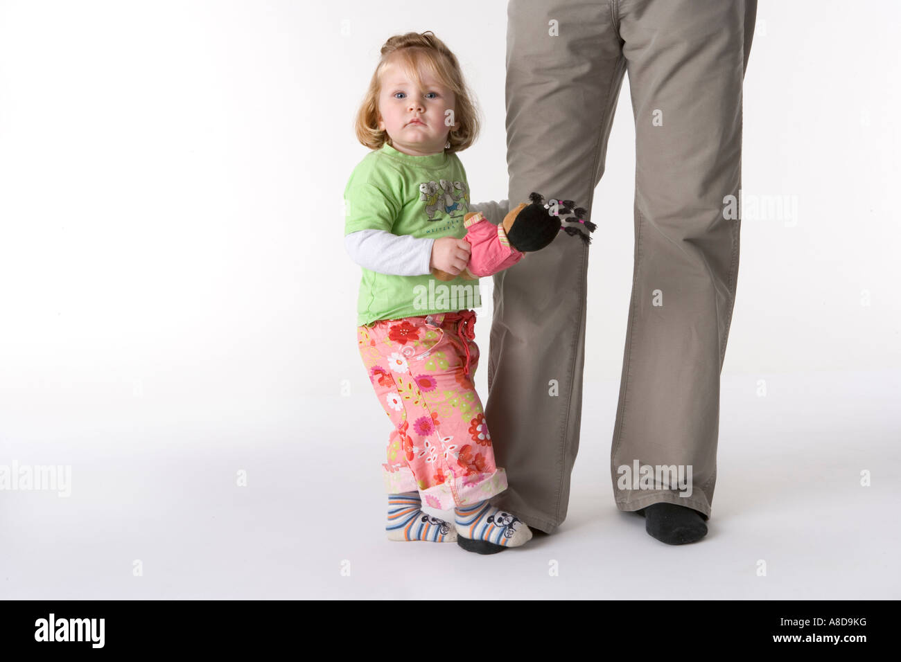 Little girl holding on to her fathers legs Stock Photo - Alamy