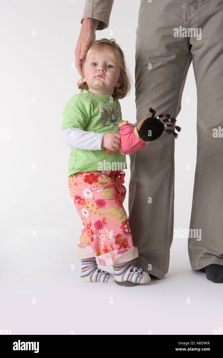 Little girl holding on to her fathers legs Stock Photo - Alamy