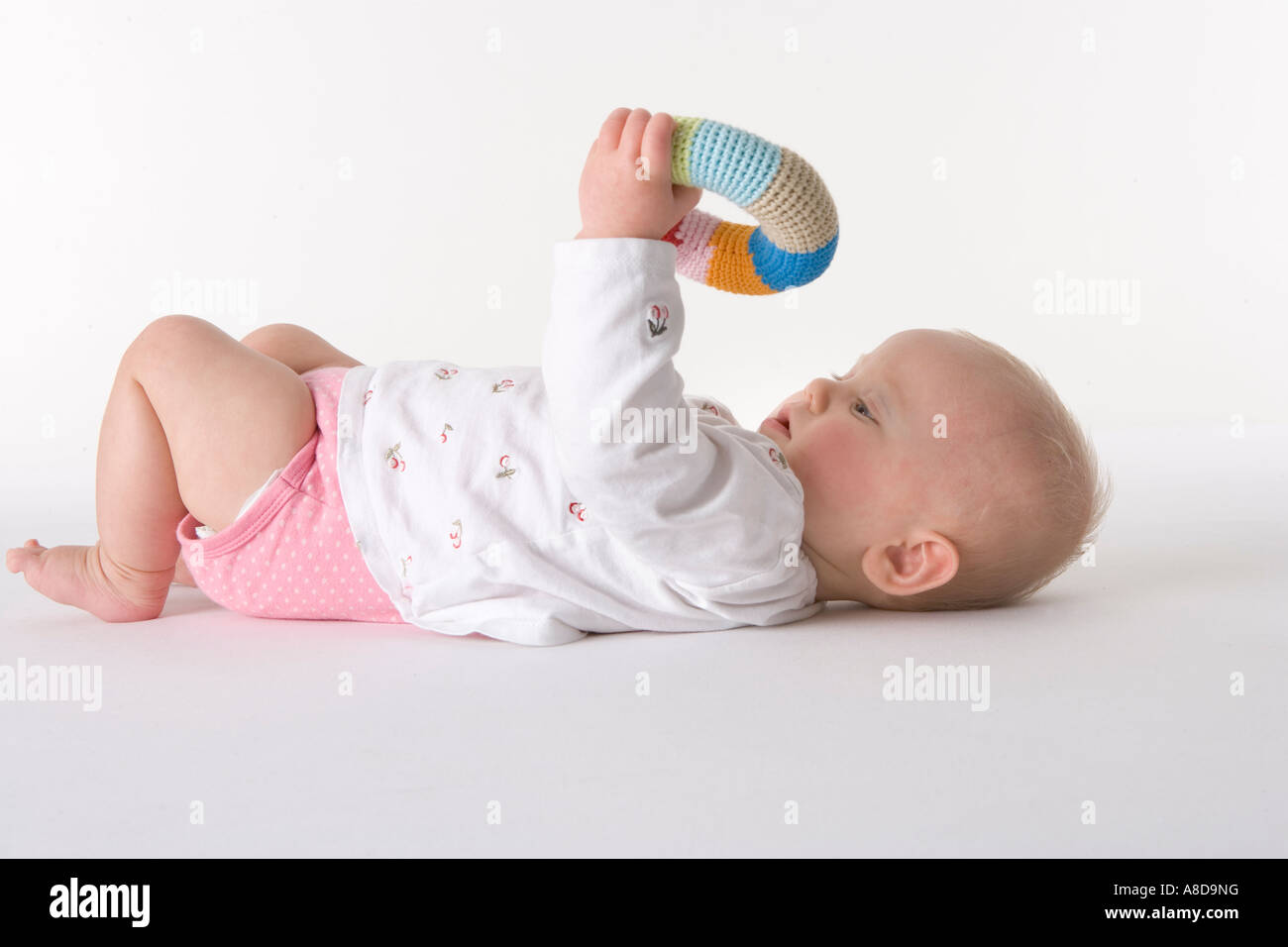 Baby lying on her back looking at a toy Stock Photo - Alamy