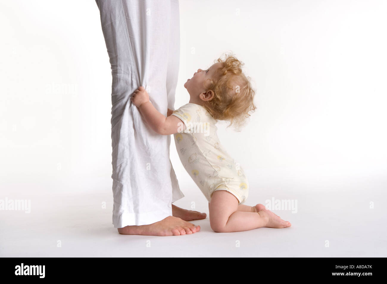 Baby girl holding on to her parents legs Stock Photo - Alamy