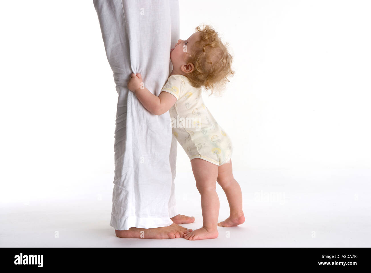 Baby girl holding on to her parents legs Stock Photo - Alamy