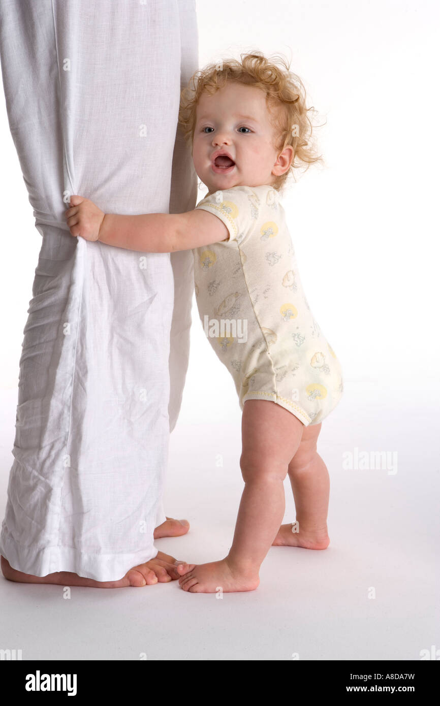 Baby girl holding on her parents legs Stock Photo - Alamy