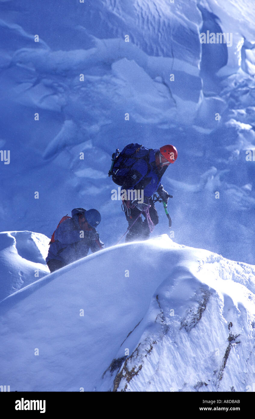 mountain Guide with client reaching summit ridge in strong wind Stock ...