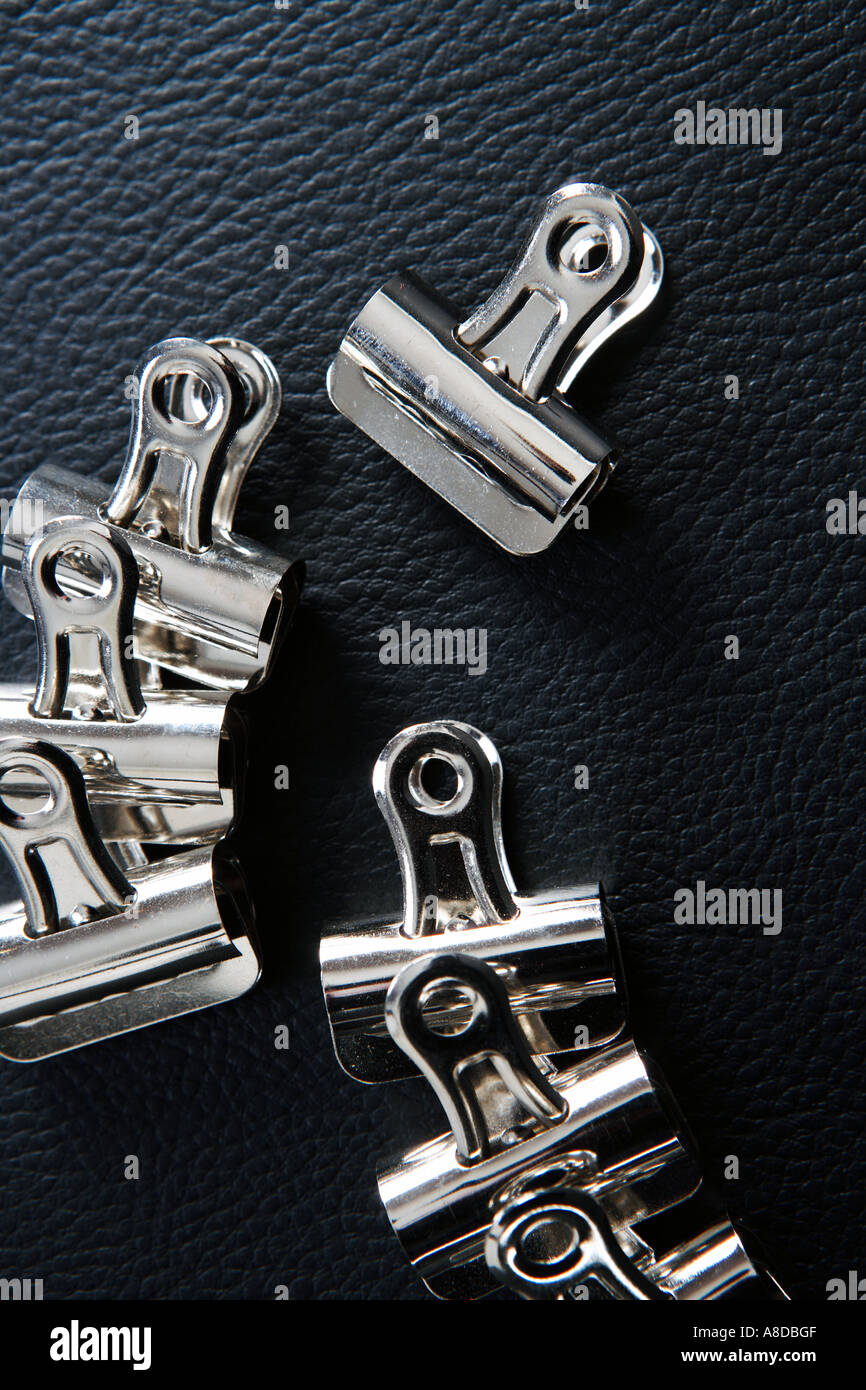 Silver bulldog clips on black setting Stock Photo - Alamy