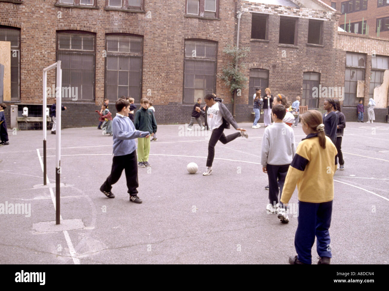 Primary school children playing football in playground Stock Photo - Alamy