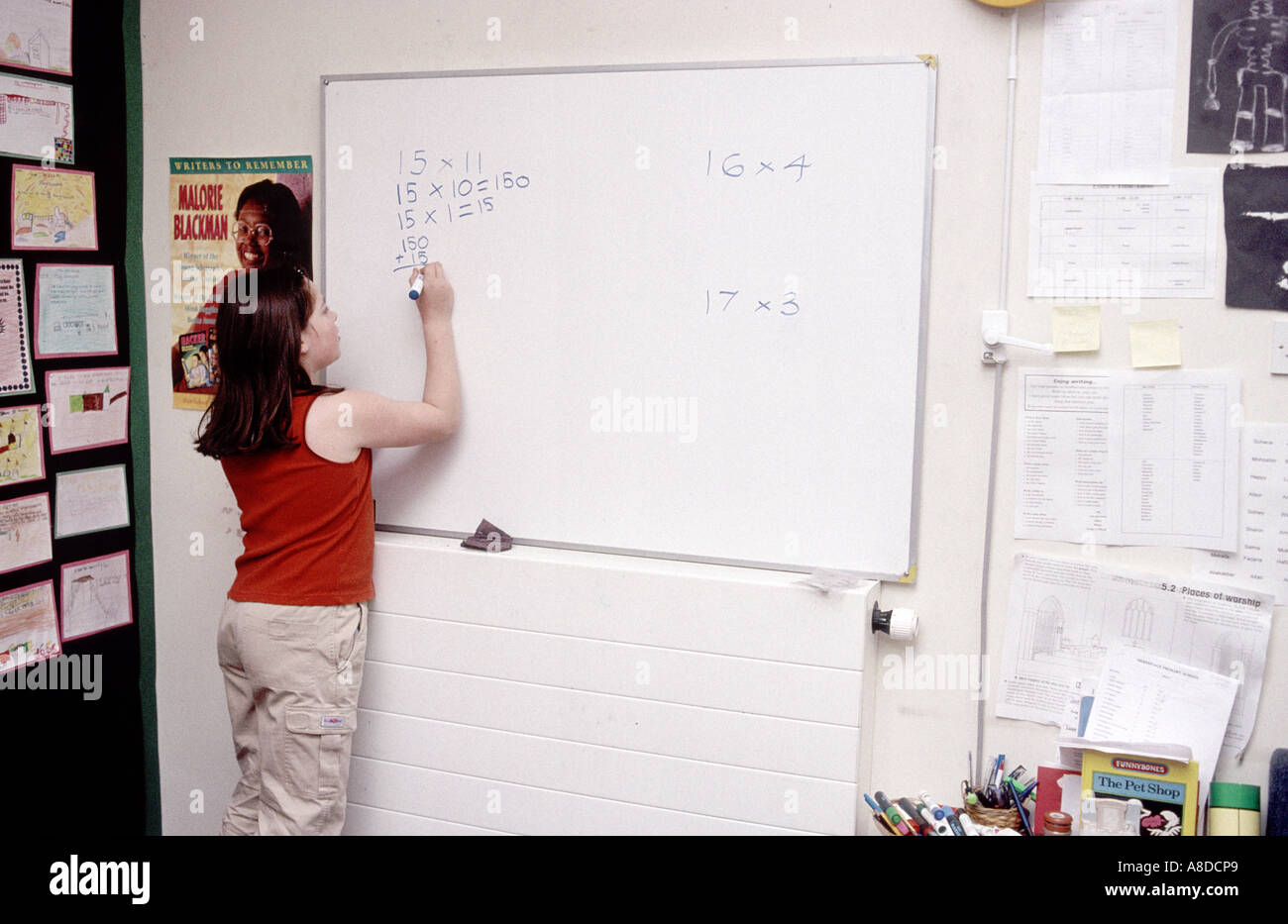 Primary school classroom with girl at white board doing multiplication ...