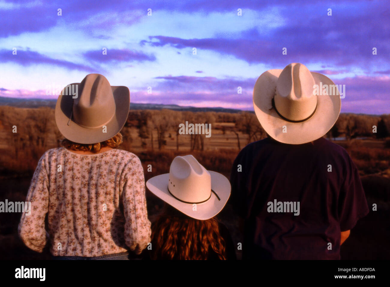 Three girls in cowboy hats viewing mountains Stock Photo - Alamy
