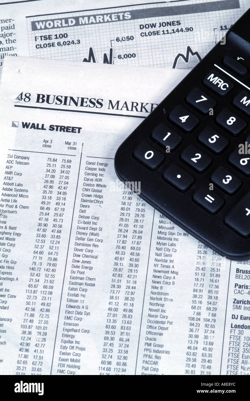 checking list of stocks and shares markets in detail on newspaper page ...