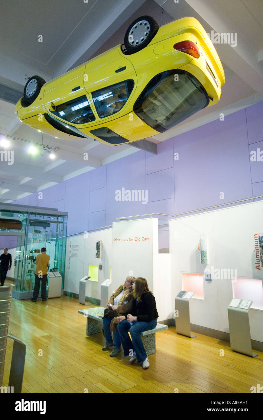 People inside the Science Museum sit beneath a car that is attached to ...