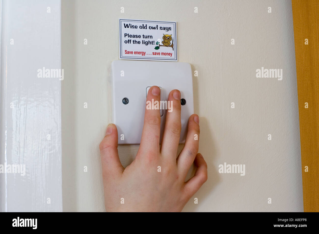 Hand turning off light switch with energy saving sticker above UK Stock ...
