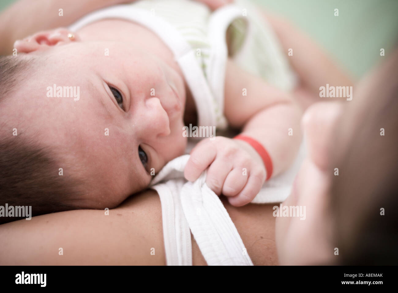 Young baby laying down on her mother Stock Photo - Alamy