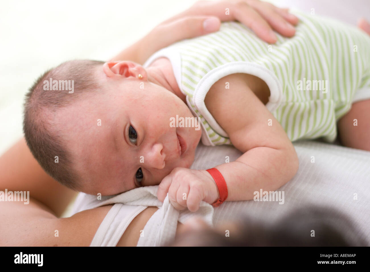 Young baby laying down on her mother Stock Photo - Alamy