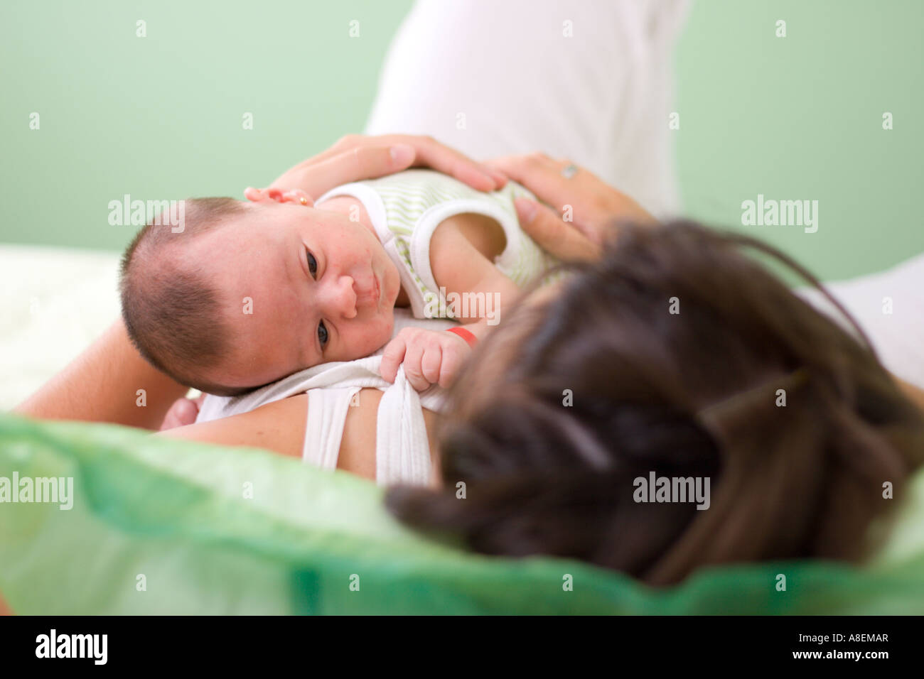 Young baby laying down on her mother Stock Photo - Alamy