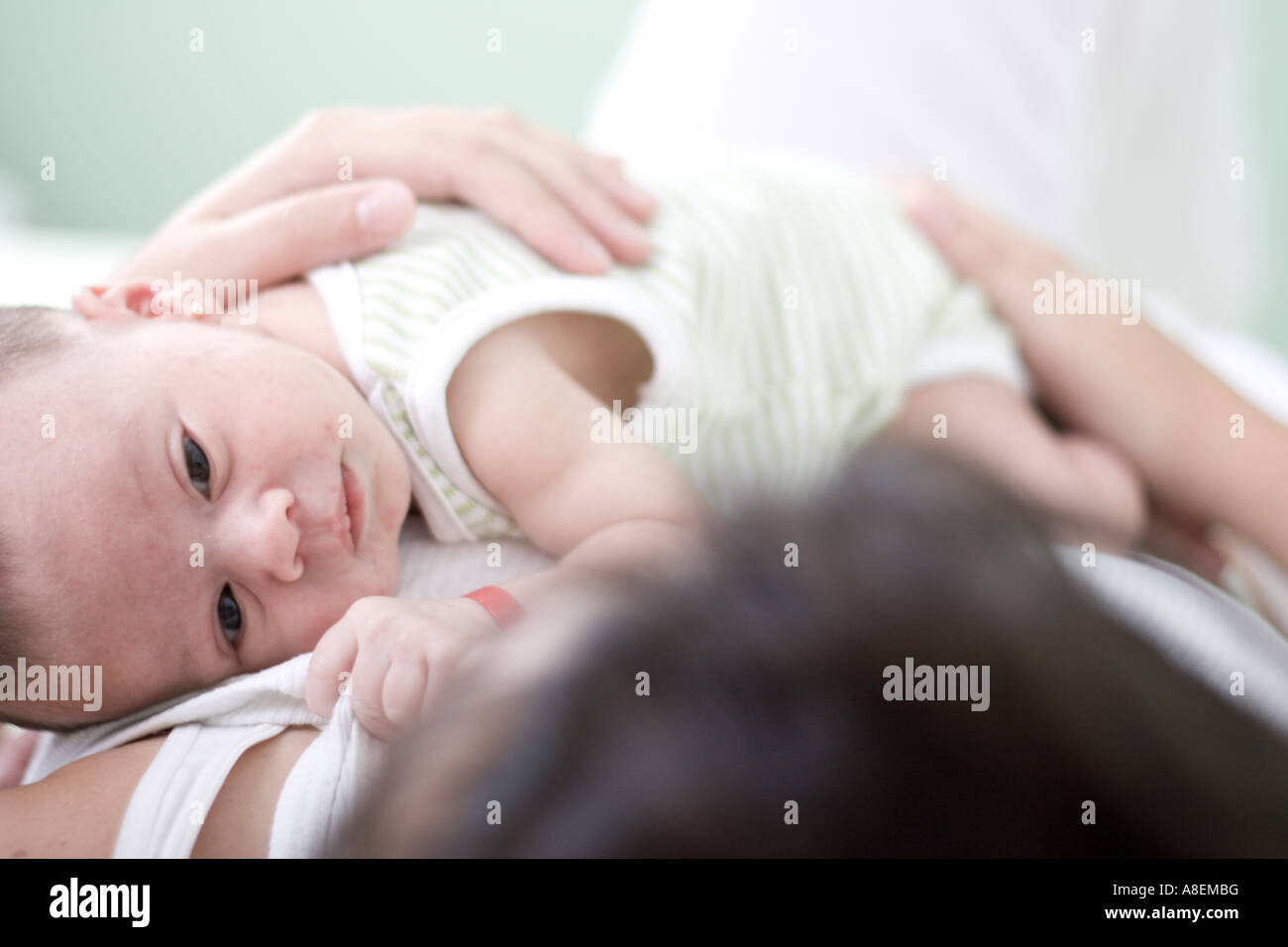 Young baby laying down on her mother Stock Photo - Alamy