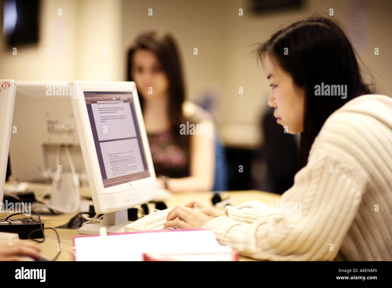Young feamle chinese student is working at a computer, a european girl ...