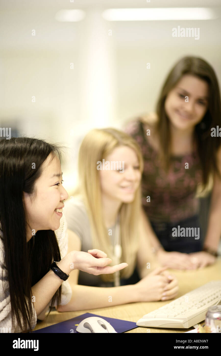 Group of young female students looking towards computer screen happy ...