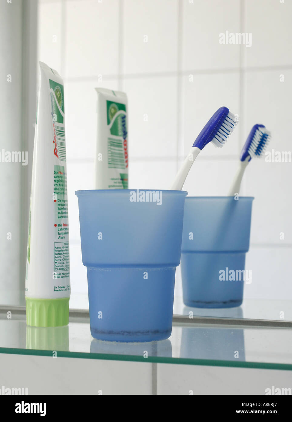Toothbrush in blue plastic cup and toothpaste in front of mirror Stock ...