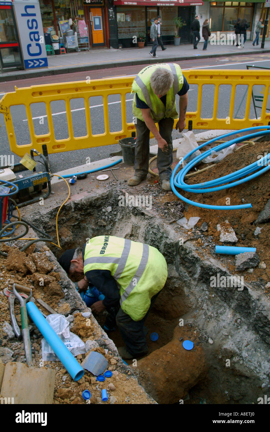 WORKERS DIGGING AND INSTALLING THE PIPES ON THE ROAD LONDON Stock Photo ...