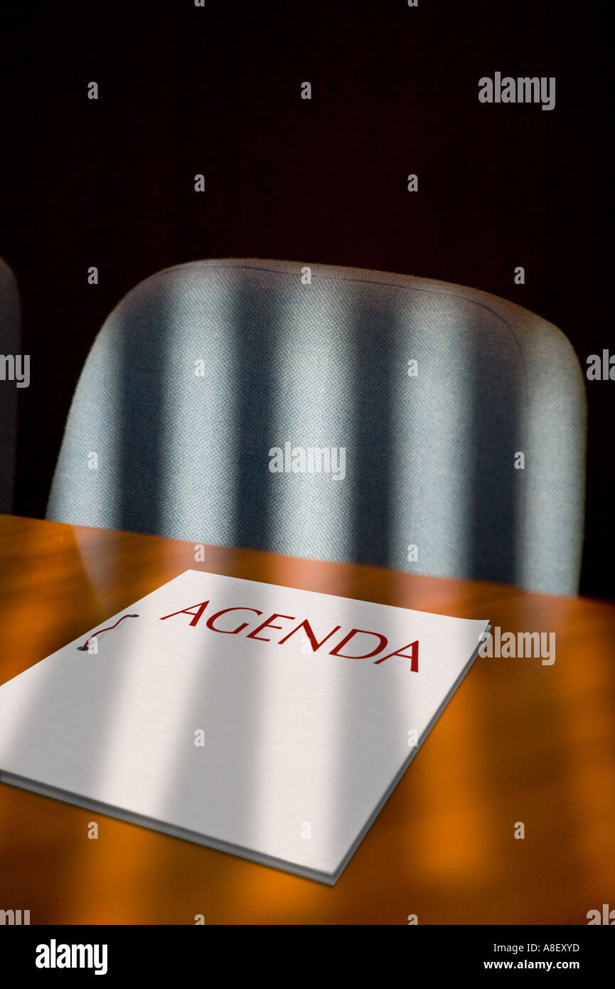 WOODEN BOARDROOM TABLE AND CHAIR WITH SHADOWS OF BLIND ON AGENDA FILE ...