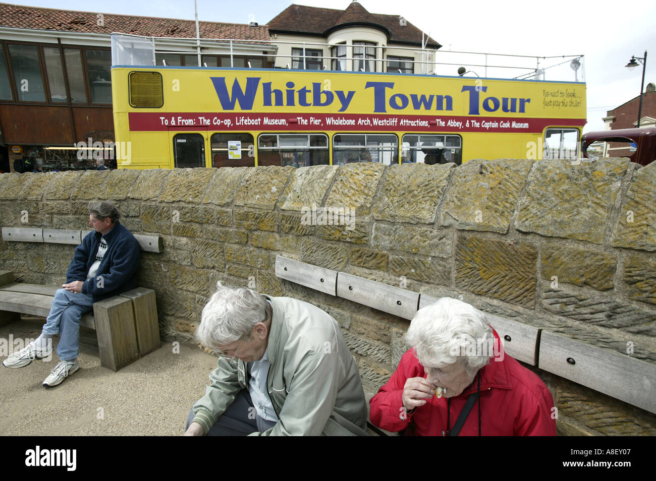 Visitors to the seaside town of Whitby sit as a tour bus passes by ...