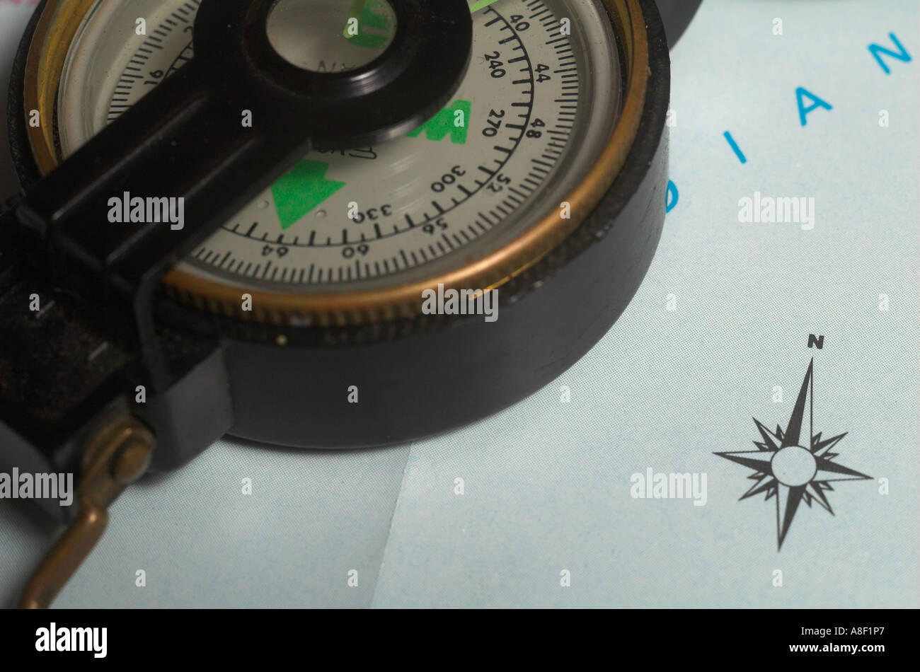 An open compass sits on top of a colourful map Stock Photo - Alamy
