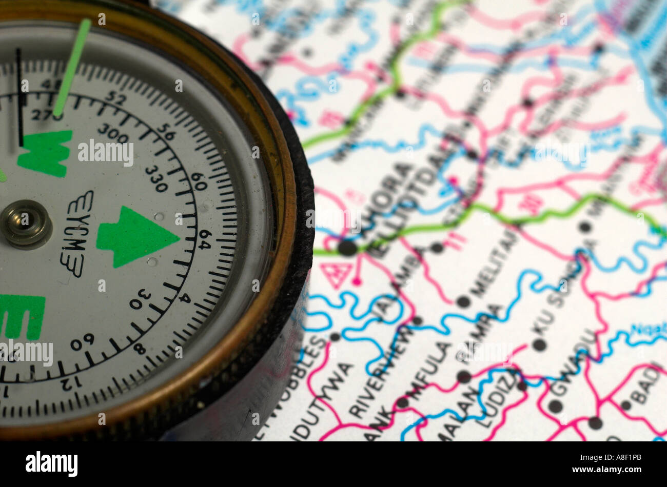 An open compass sits on top of a colourful map Stock Photo - Alamy