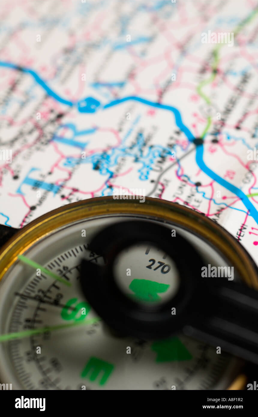 A needle compas lies on top of a colourful map Stock Photo - Alamy