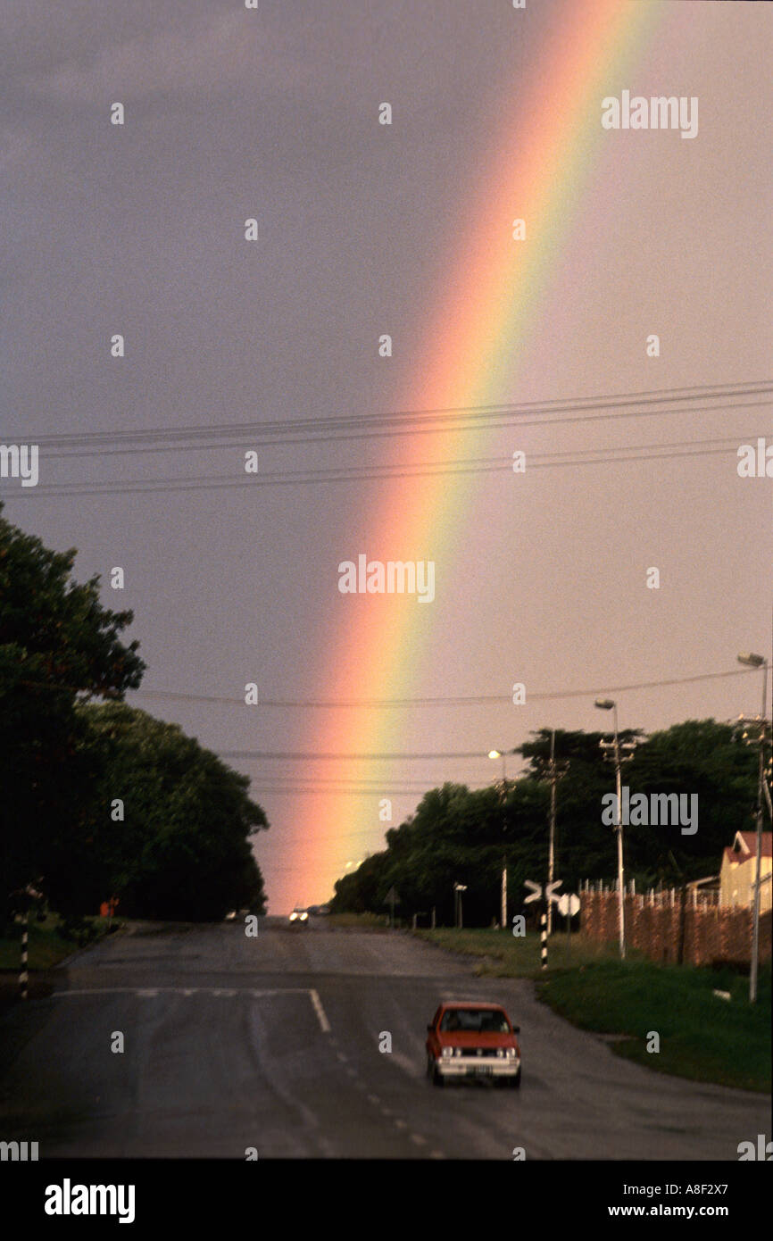 A colourful rainbow starts in the middle of a long straight road Stock ...