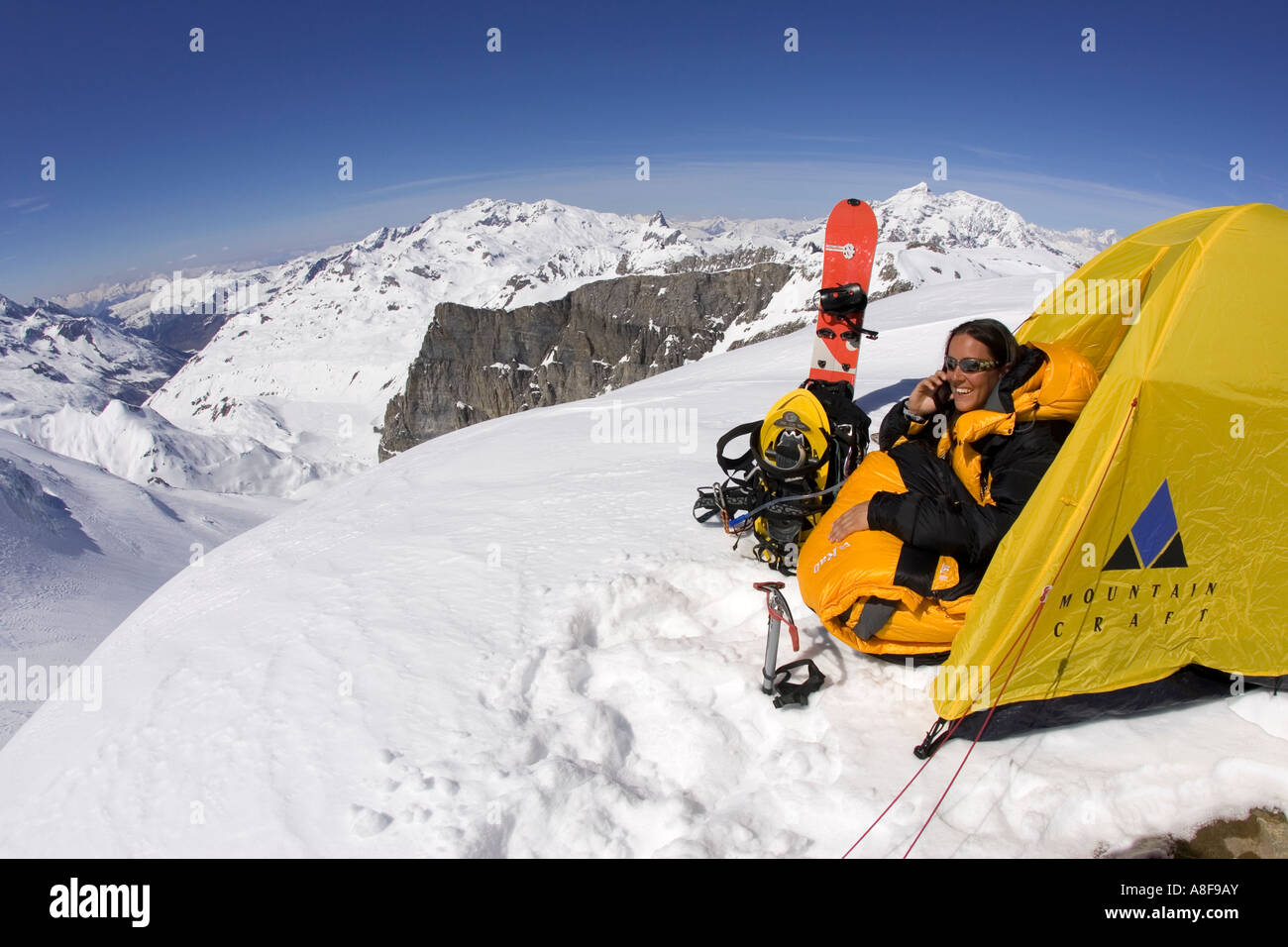 Female mountaineer makes cell / sat phone call from camp in Alpine ...
