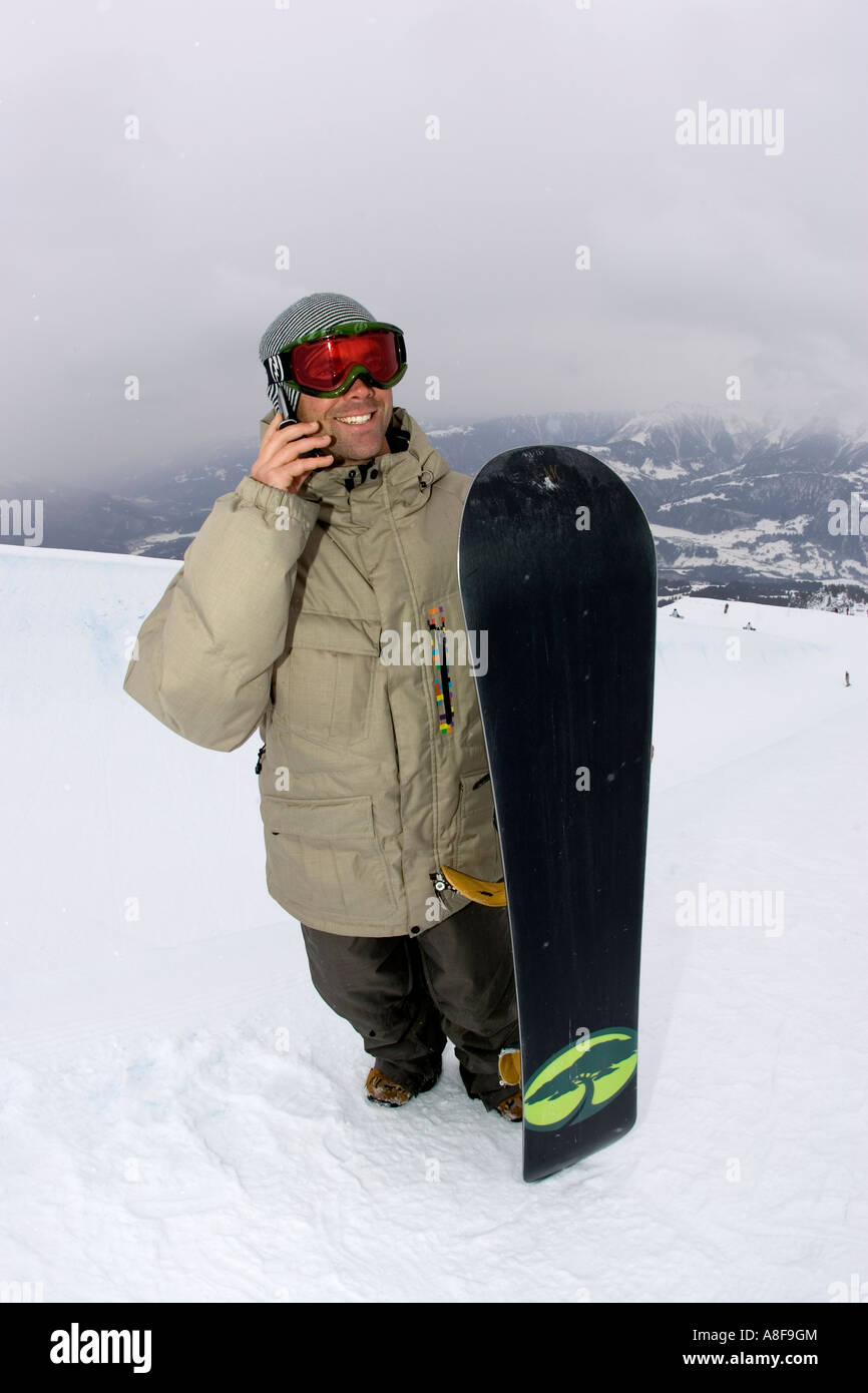 Snowboarder making Cell mobile phone call from snowy mountain Stock ...