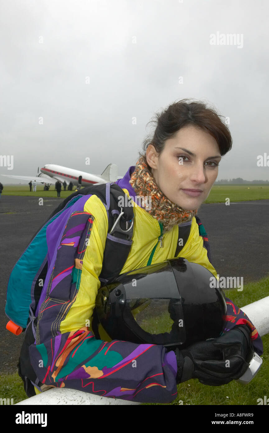 Young woman wearing parachute gear waiting outside a small airport ...