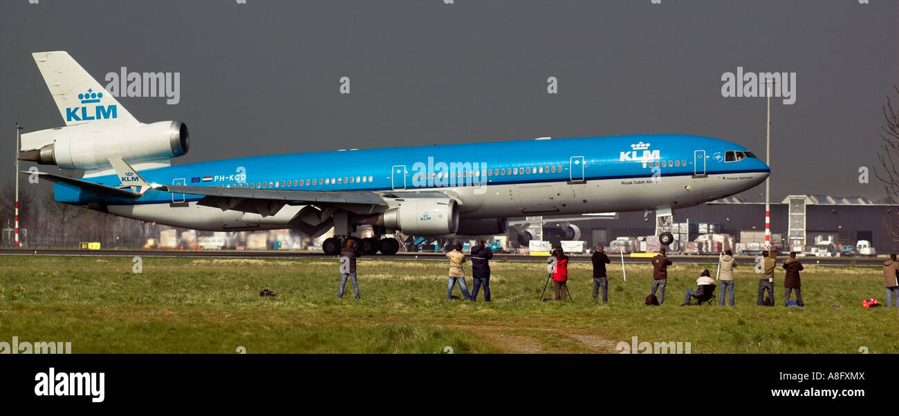 Plane spotters watch a KLM Boeing MD11 land under a stormy sky at ...