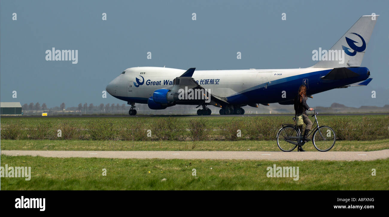 A girl on a bike watches a Boeing 747 Jumbo Jet take off from Schipol ...