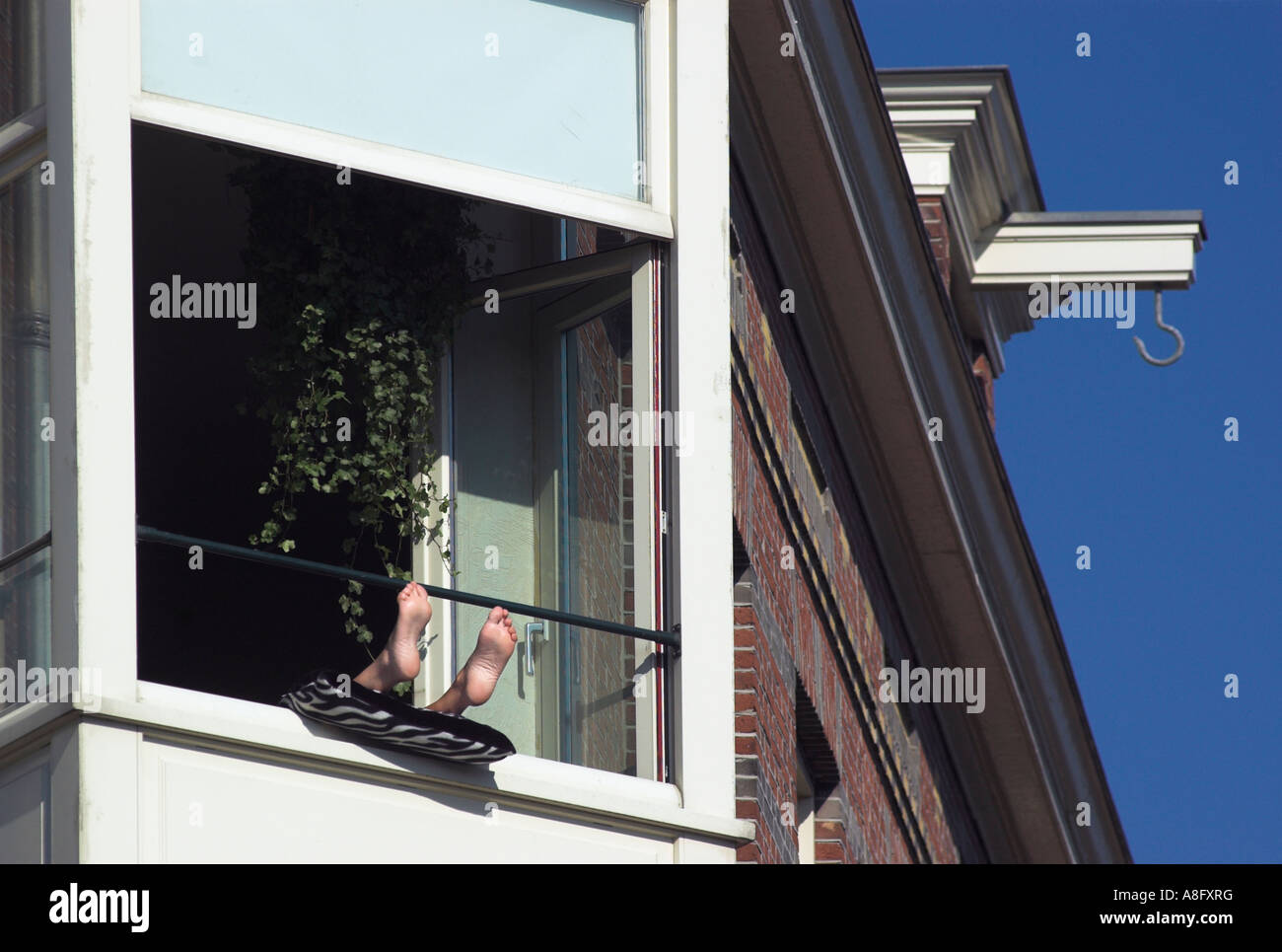 A sunbathers feet sticking out of the window of an apartment in ...