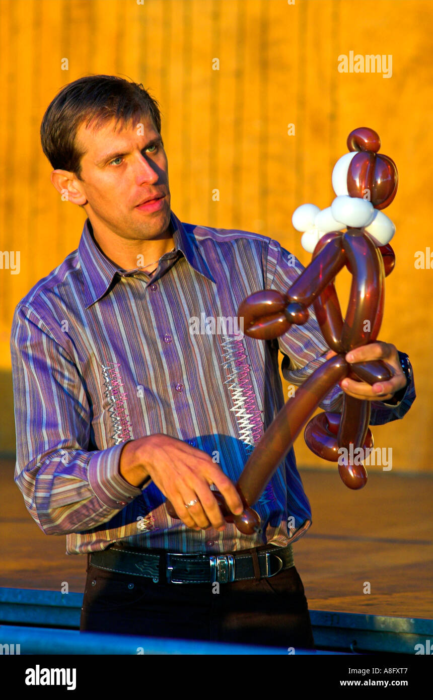 A street entertainer creating balloon sculptures in the summer sunset ...