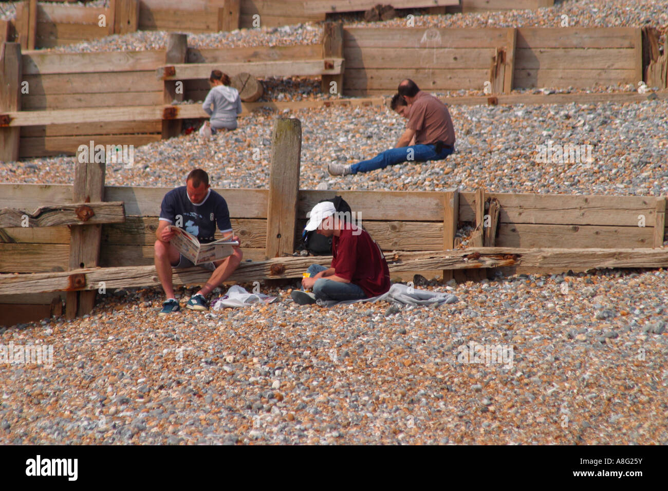 People reading the Sunday Newspapers on a South coast beach in the UK ...