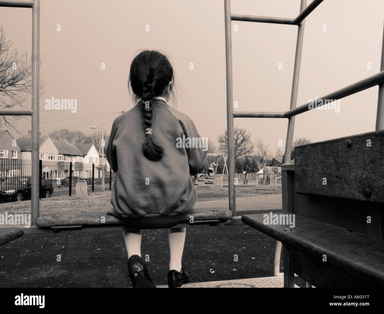 Lone child in a school uniform sitting alone on a playground ,London ...