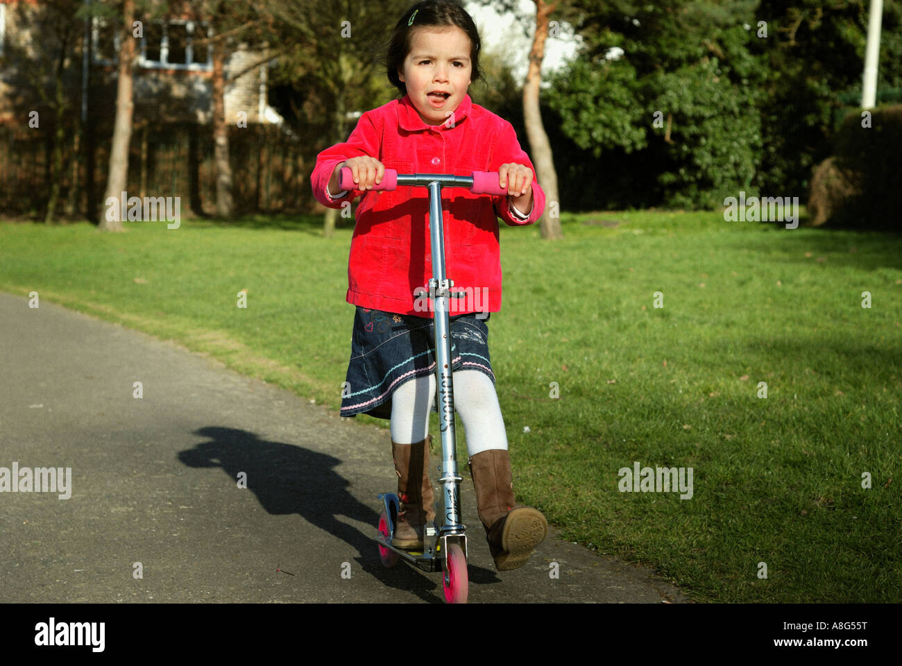Young child enjoys racing on her scooter Stock Photo - Alamy