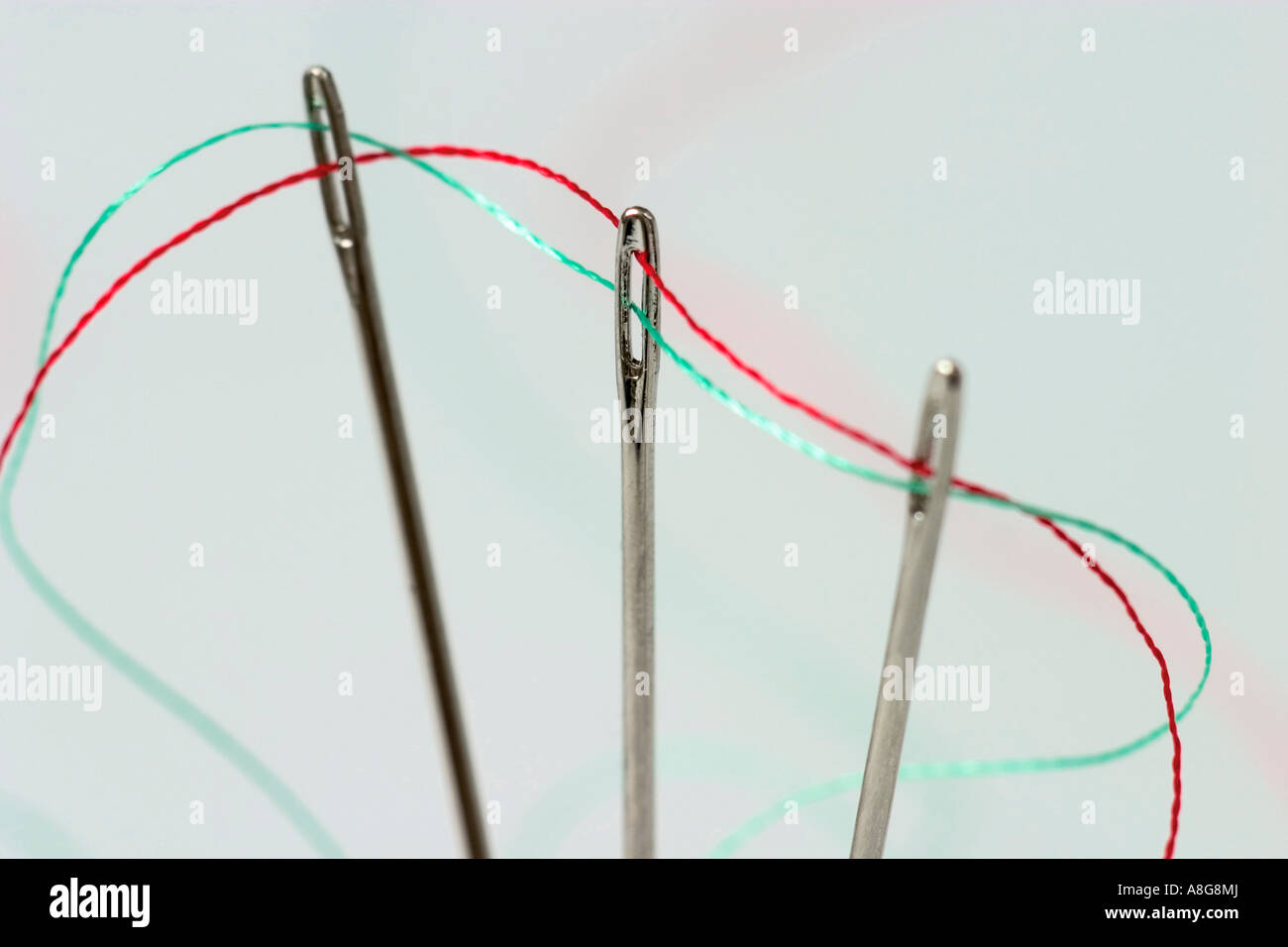 Three needles with thread of differet colors Stock Photo - Alamy
