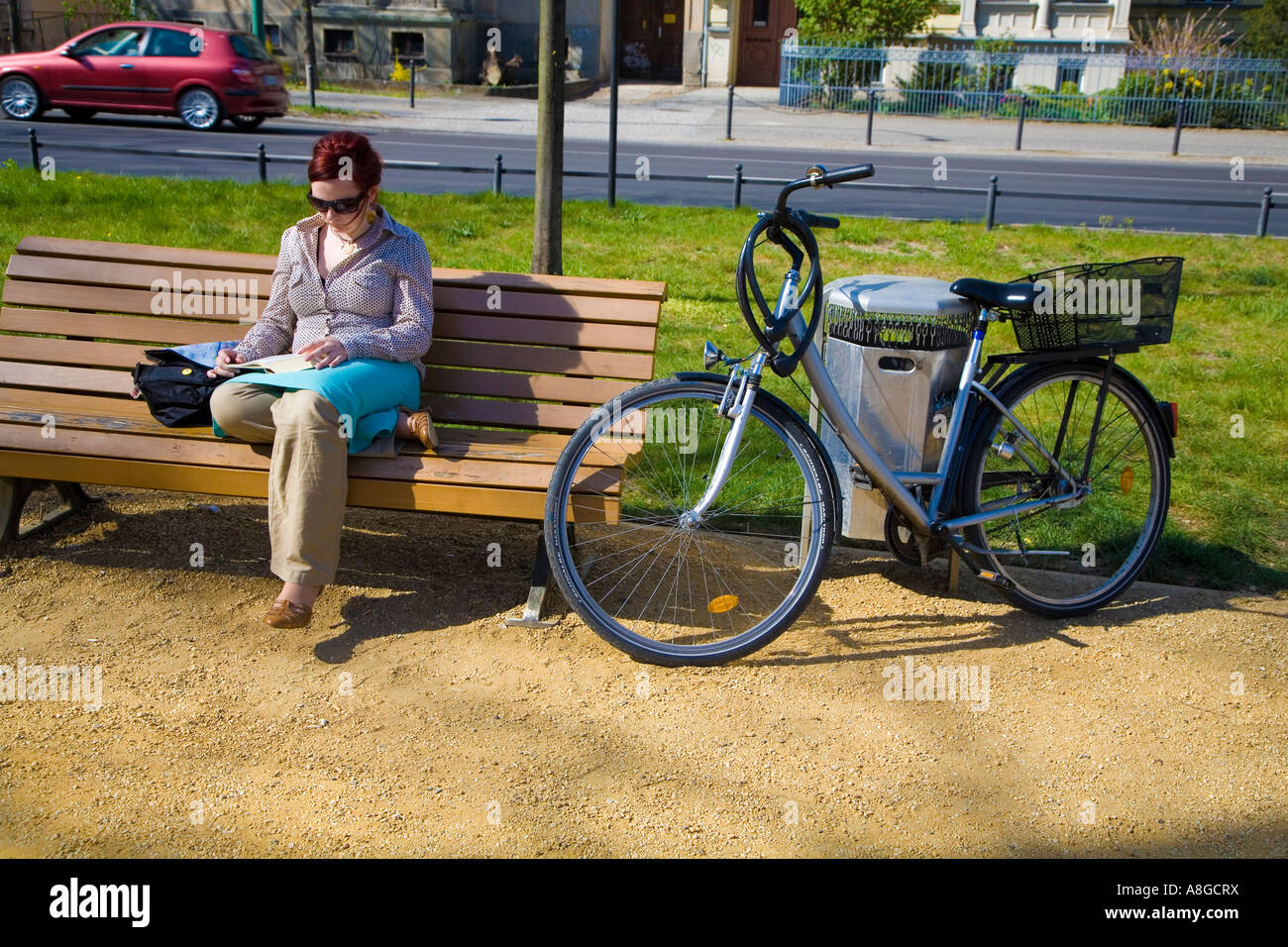 Young Woman sat on Bench Reading Stock Photo - Alamy