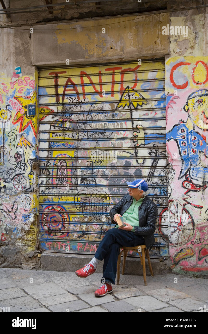 Man reading book in front of graffiti covered wall on neighborhood ...